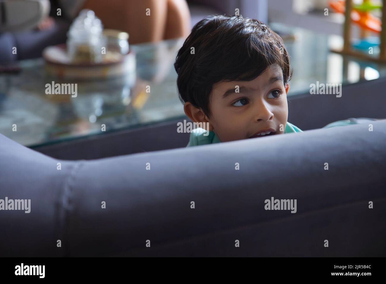 Portrait of a little child hiding behind sofa in living room Stock ...