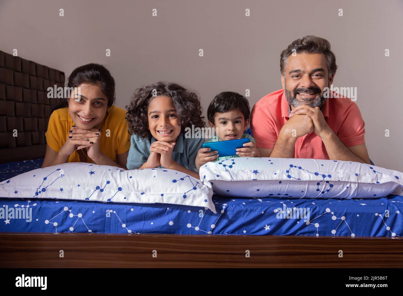 Portrait of happy family lying down together on bed Stock Photo - Alamy