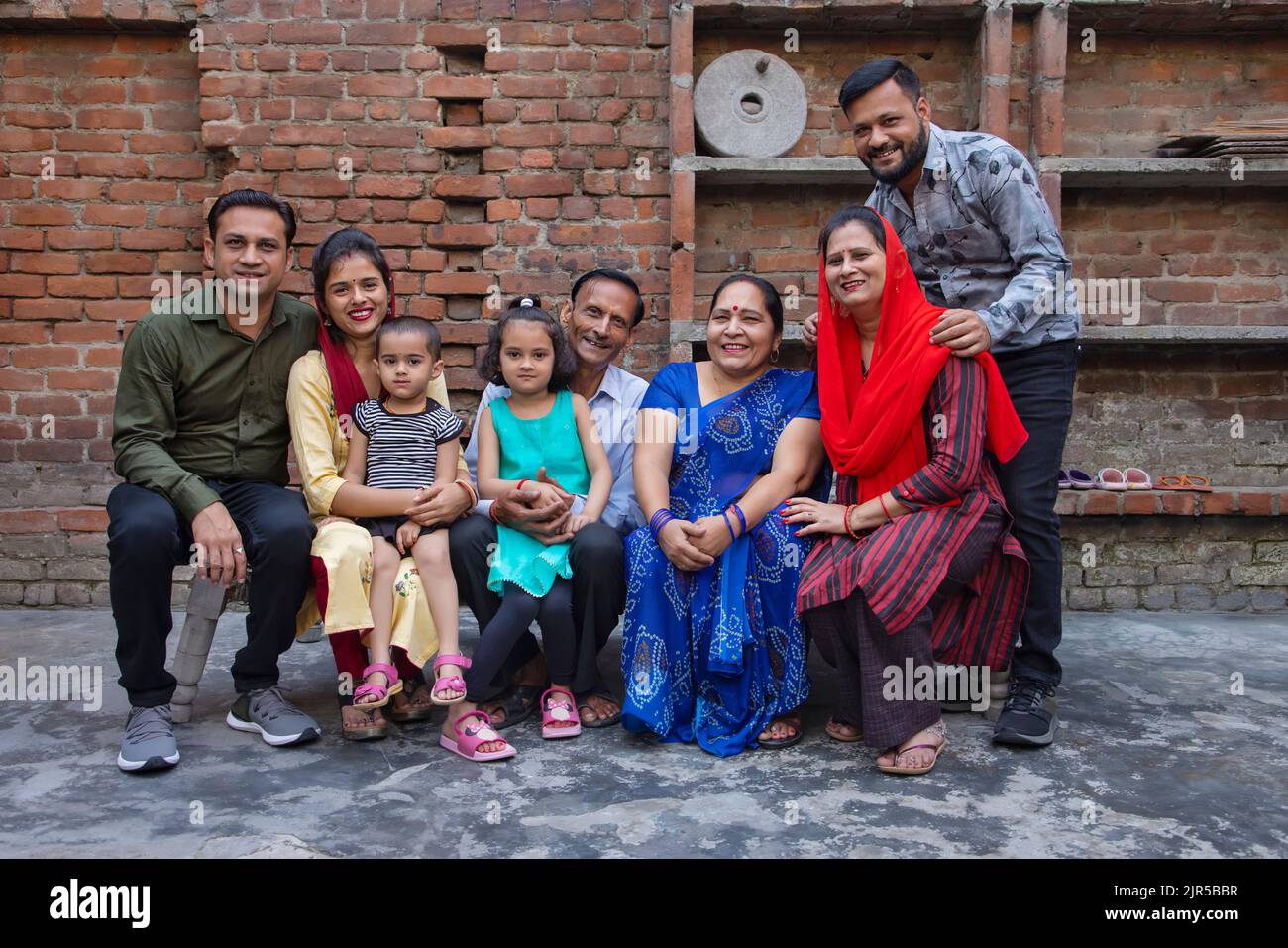 Portrait of lower middle class family sitting together on cot in the ...