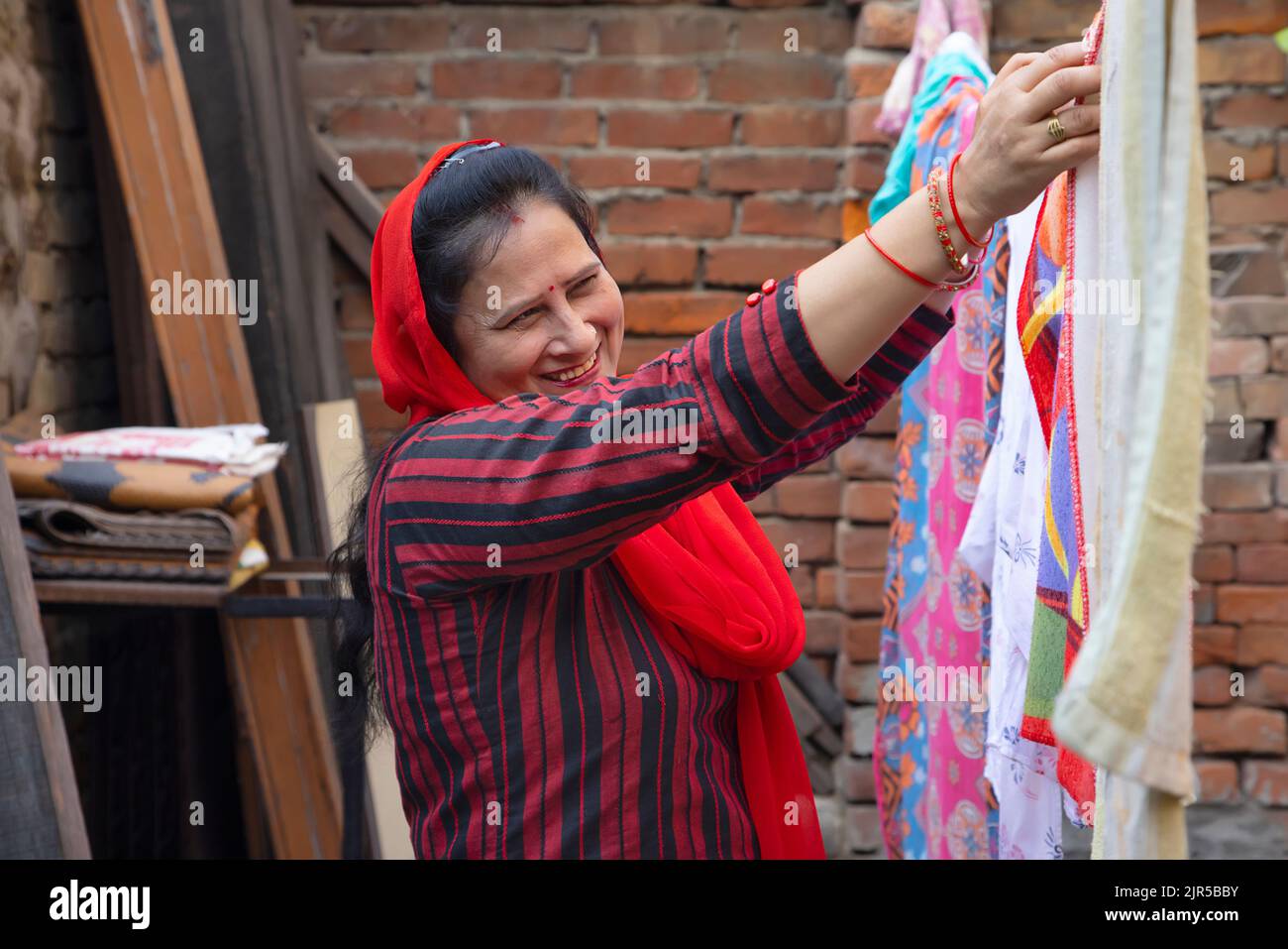 Woman hanging clothes on washing line to dry in the backyard Stock ...