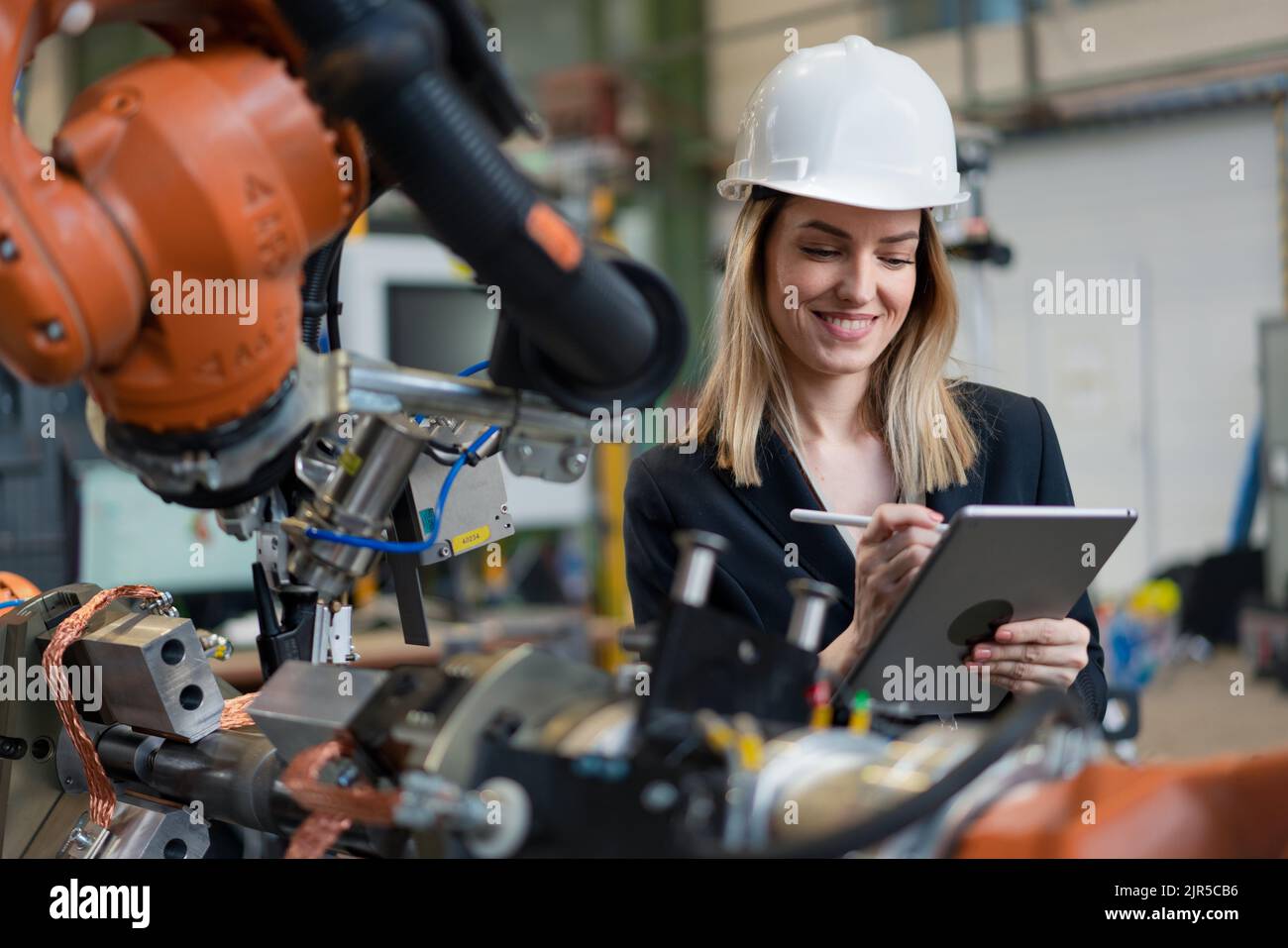 Female chief engineer in modern industrial factory using tablet and ...