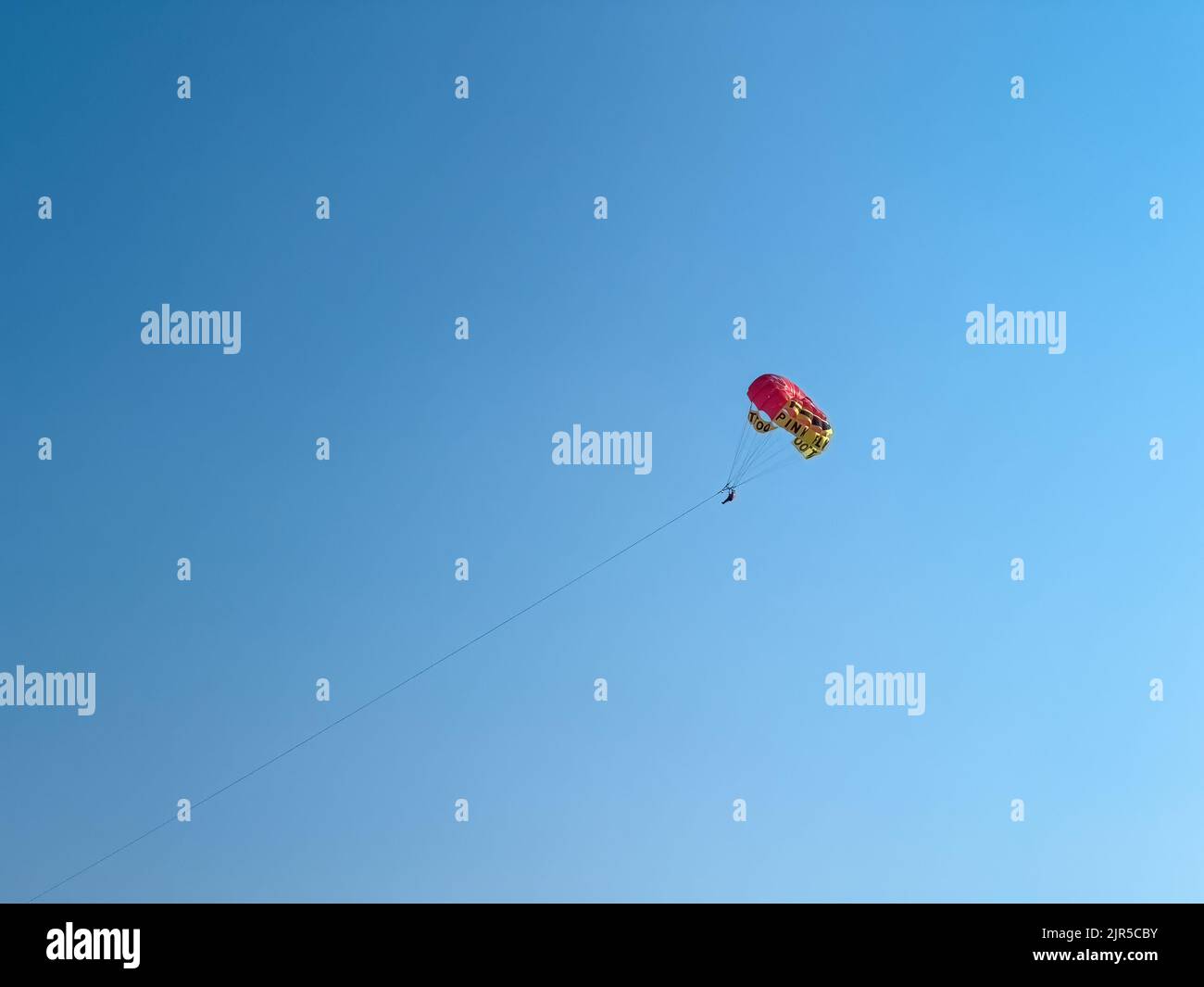 Two people parasailing with a parachute pulled by a boat on vacation at ...