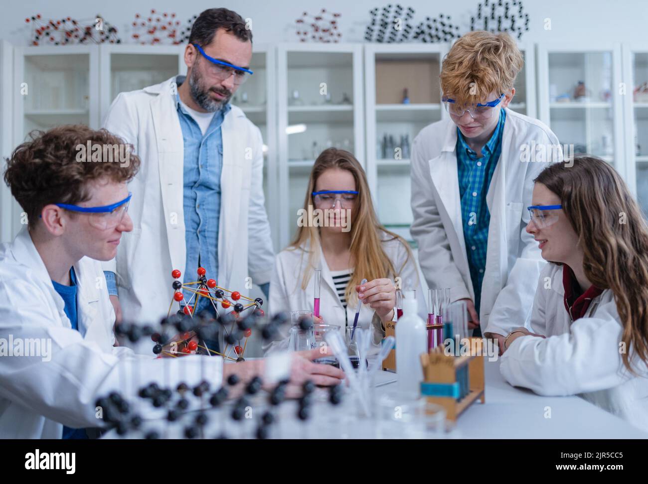 Science students with teacher doing chemical reaction experiment in the ...