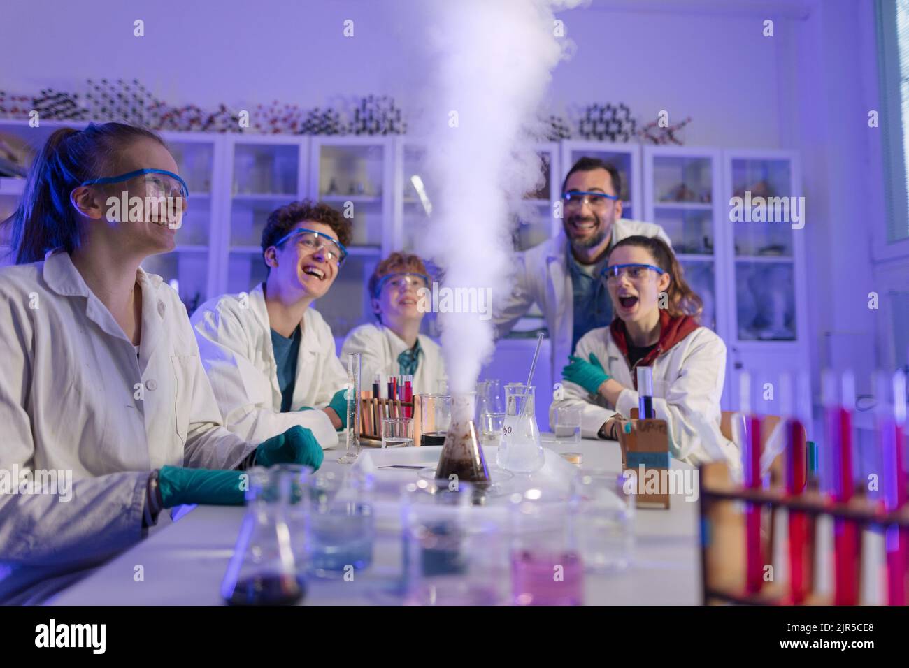 Excited science students with teacher doing chemical experiment in the ...