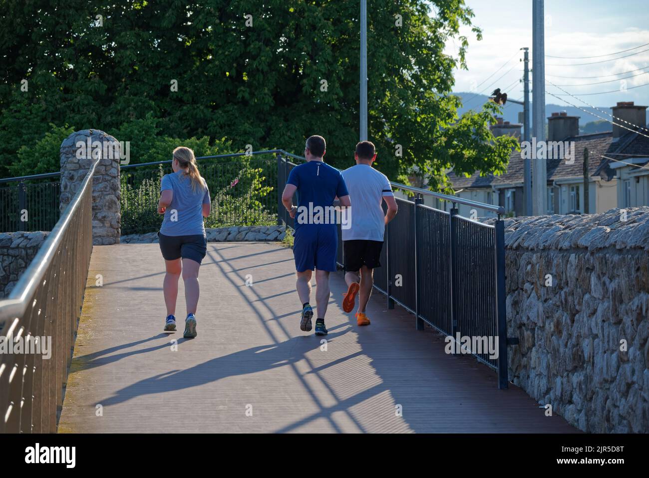 Group of people is running together exercising along the river bank on ...