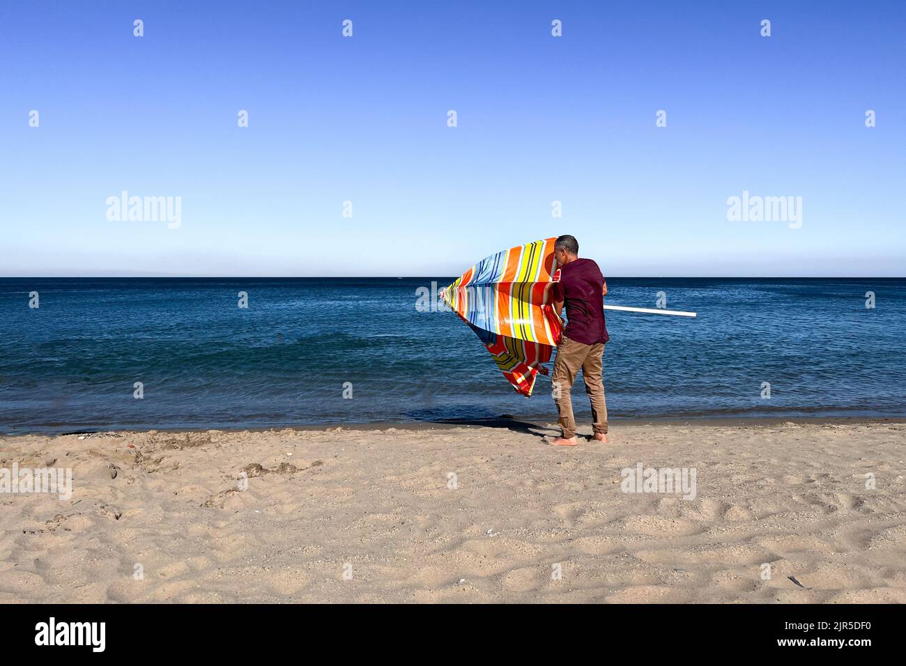 man holding an open parasol on the beach Stock Photo - Alamy