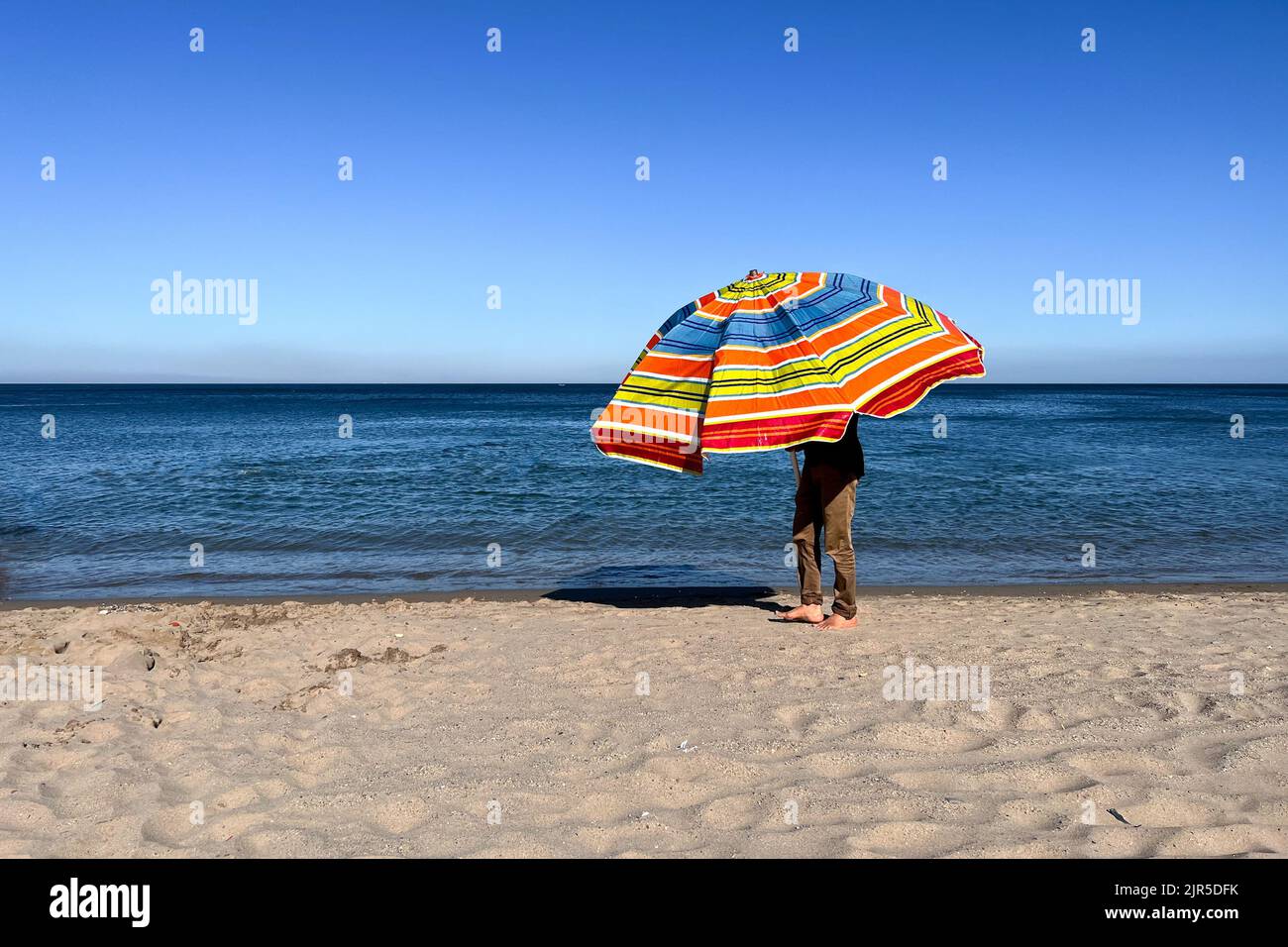 man holding an open parasol on the beach Stock Photo - Alamy
