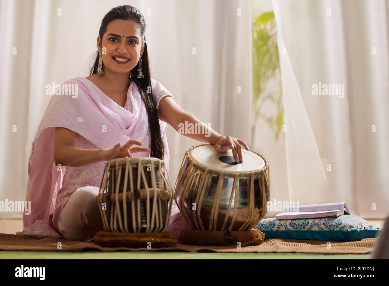 Portrait of young woman playing Tabla at home Stock Photo - Alamy