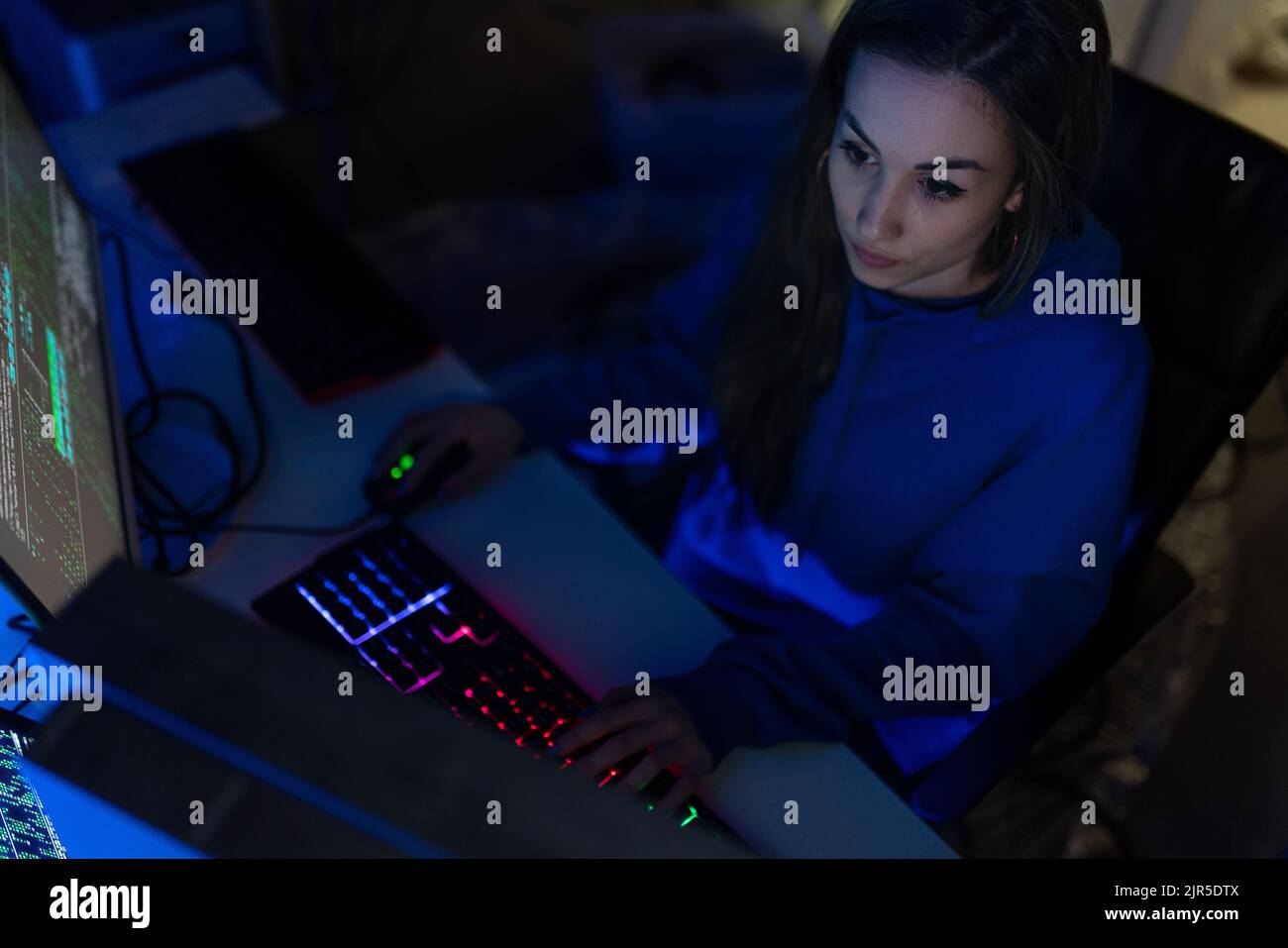 Young woman hacker by computer in the dark room at night, cyberwar ...