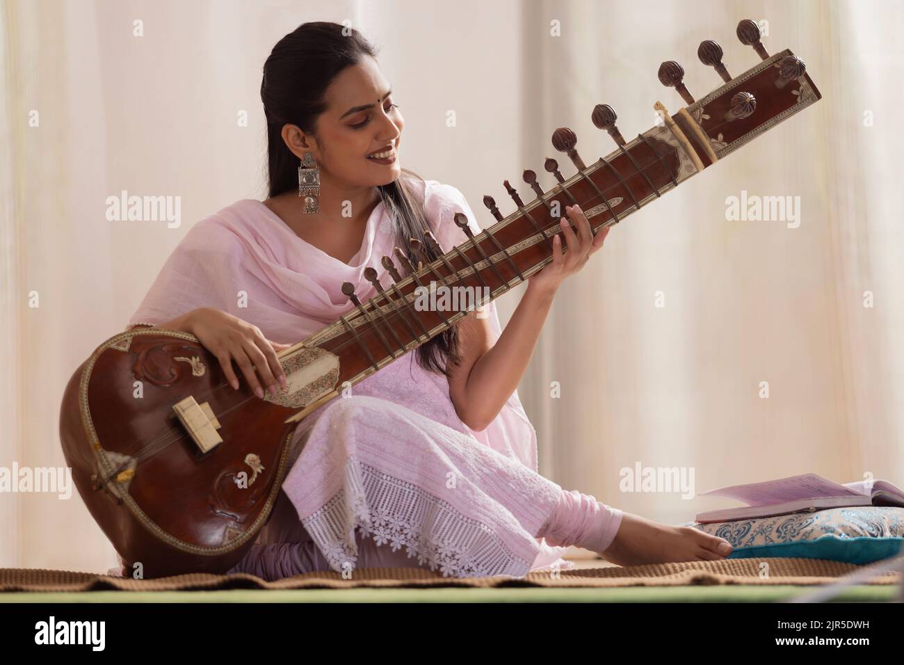 Young female musician playing Sitar at home Stock Photo - Alamy