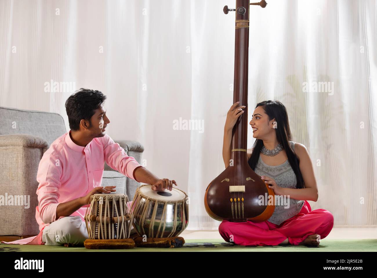 Young man and woman playing Tabla and Tanpura together at home Stock ...
