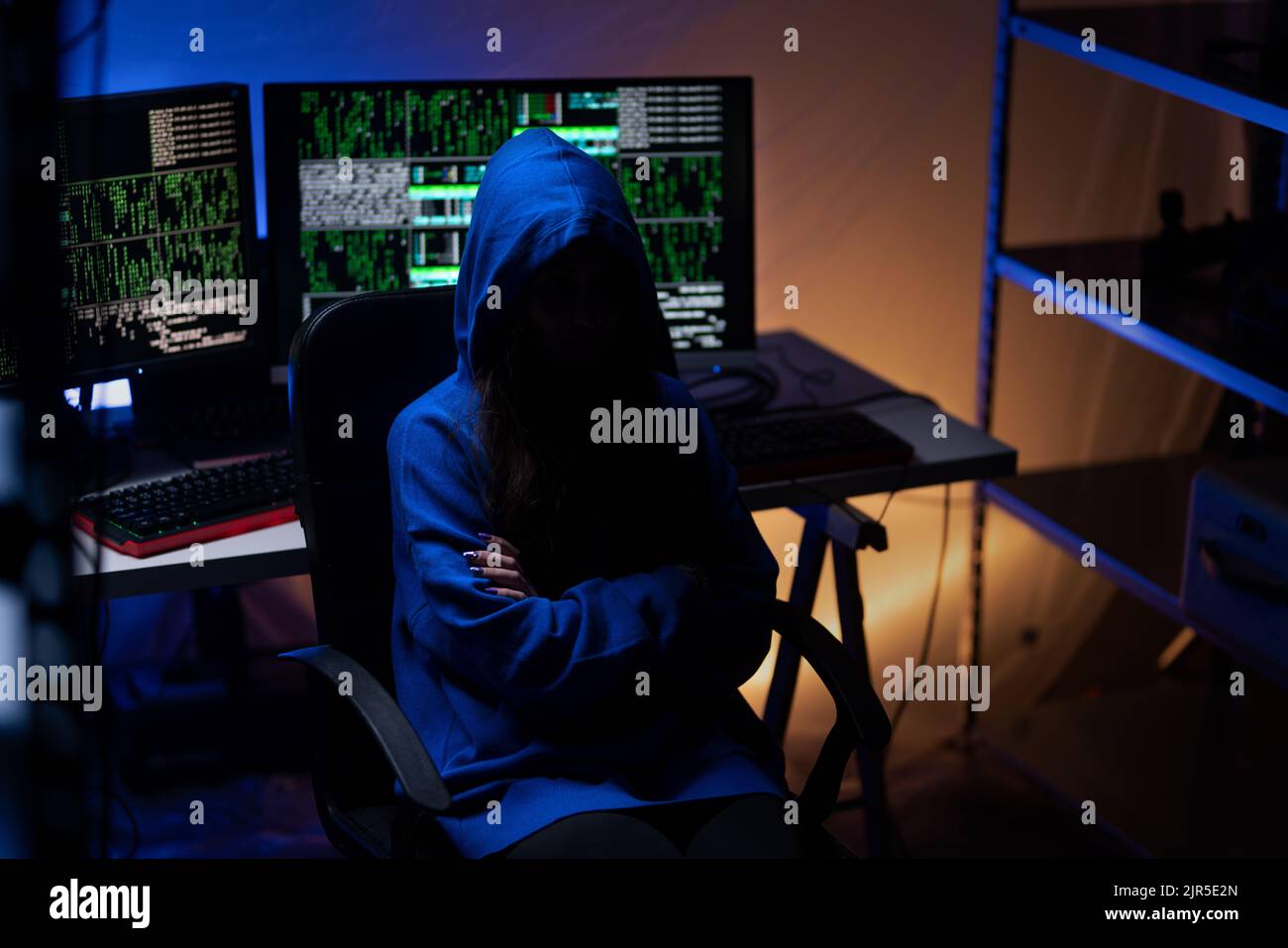 Hooded anonymous hacker by computer in the dark room at night, cyberwar ...