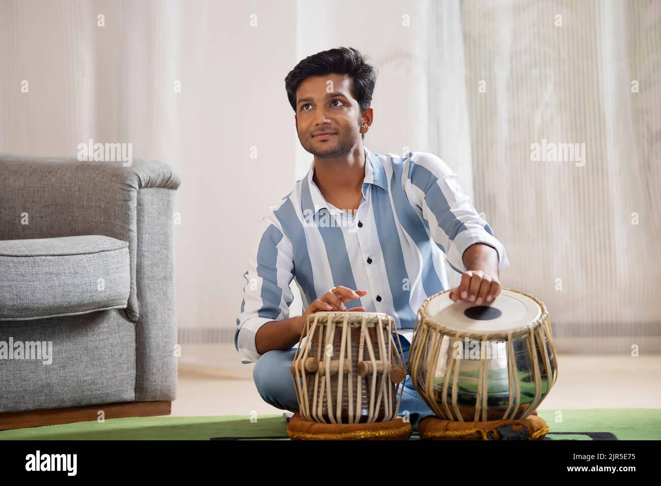 Portrait of young man playing Tabla at home Stock Photo - Alamy