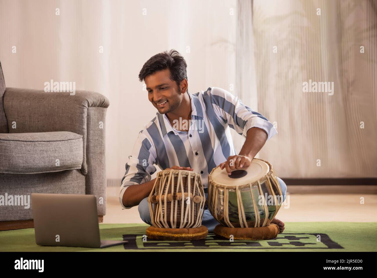 Portrait of young man having online Tabla lesson Stock Photo - Alamy