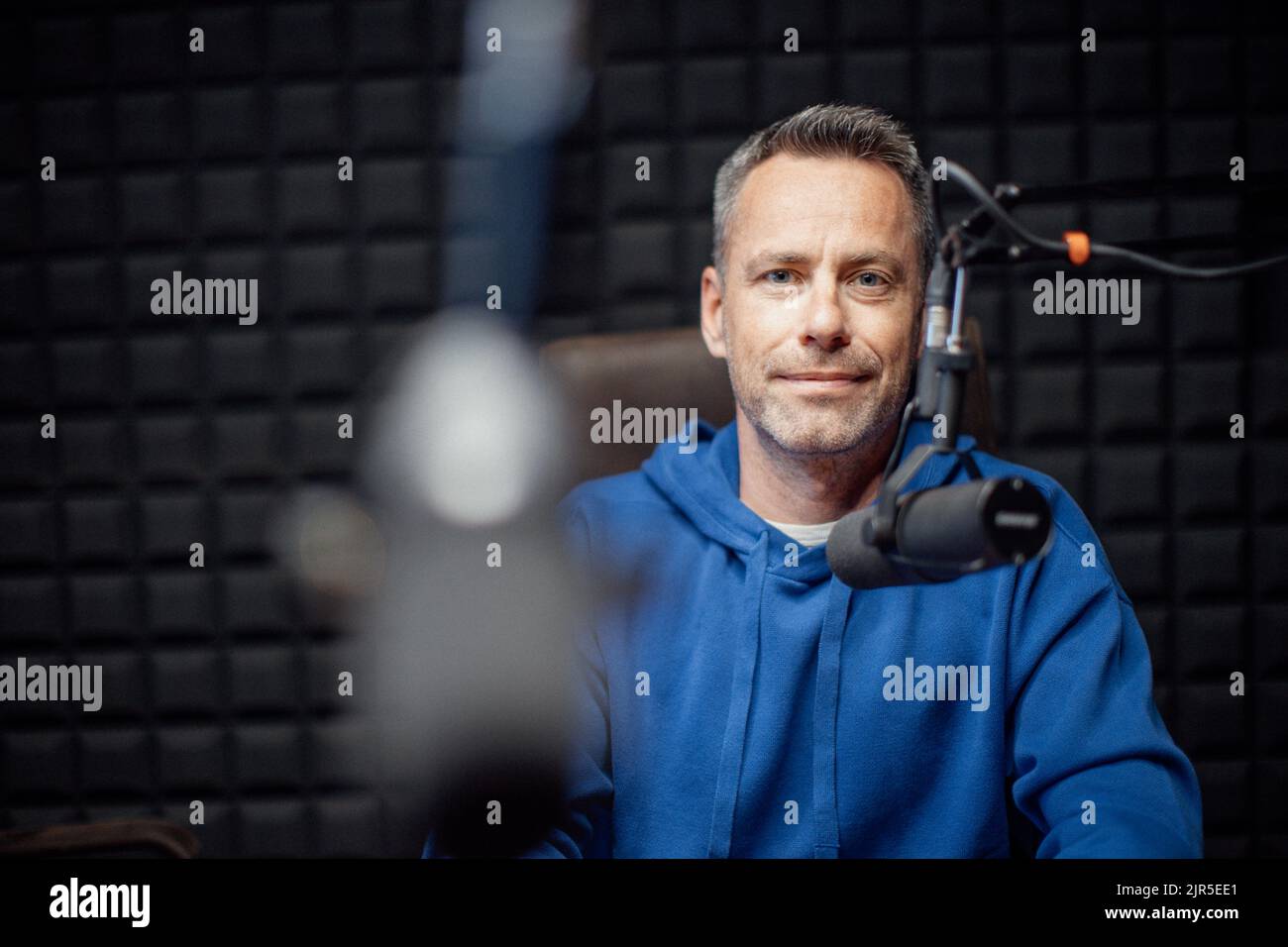 Portrait of mature radio host speaking in microphone while moderating a ...