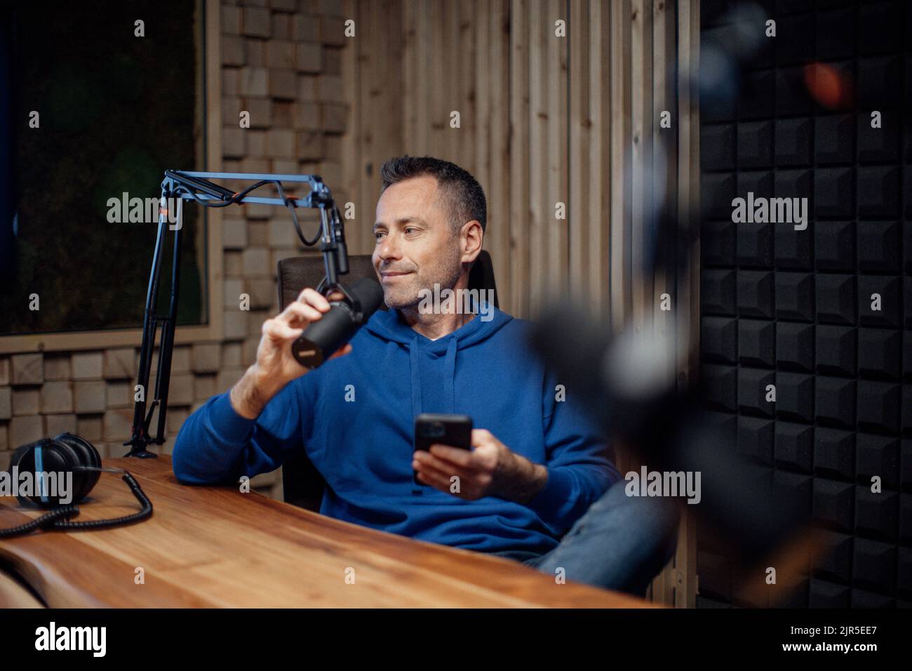 Portrait of mature radio host speaking in microphone while moderating a ...