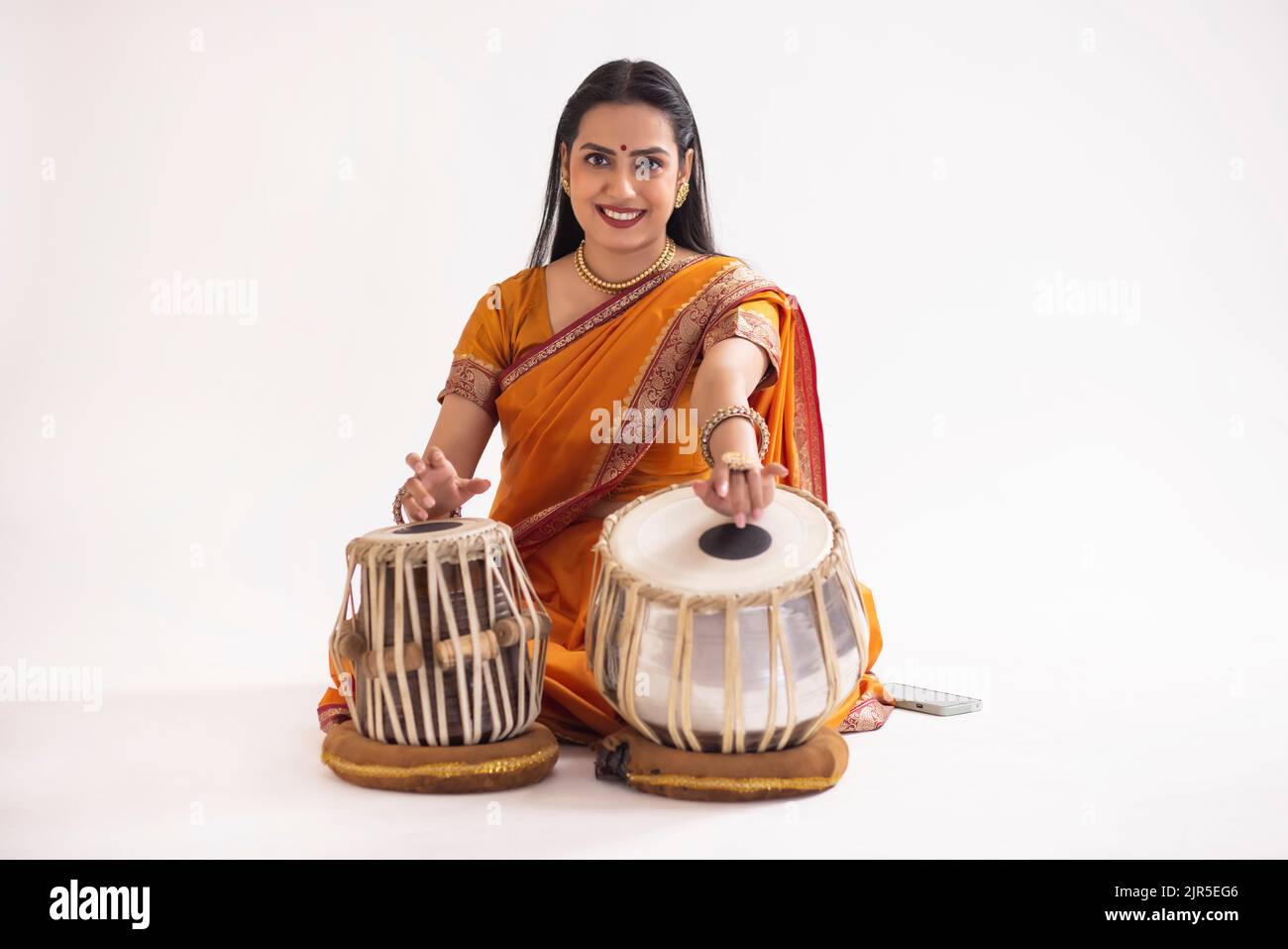 Portrait of cheerful woman in traditional outfit playing tabla Stock ...