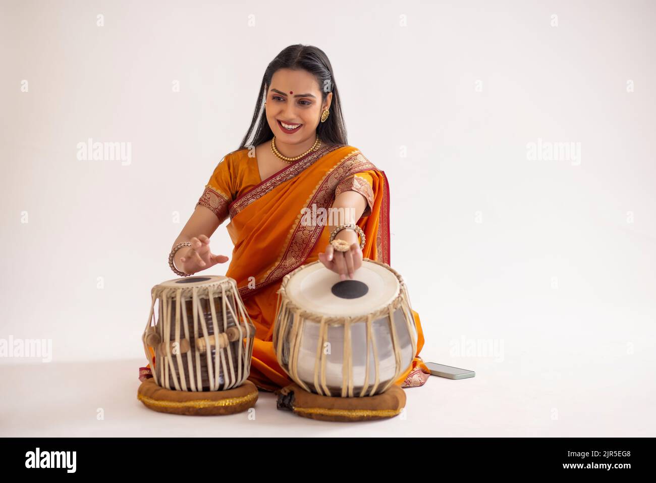 Portrait of cheerful woman in traditional outfit playing tabla Stock ...