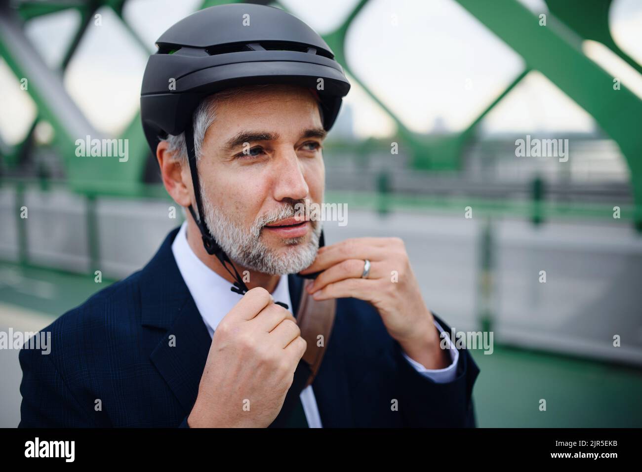 Portrait of businessman commuter on the way to work putting on cycling ...