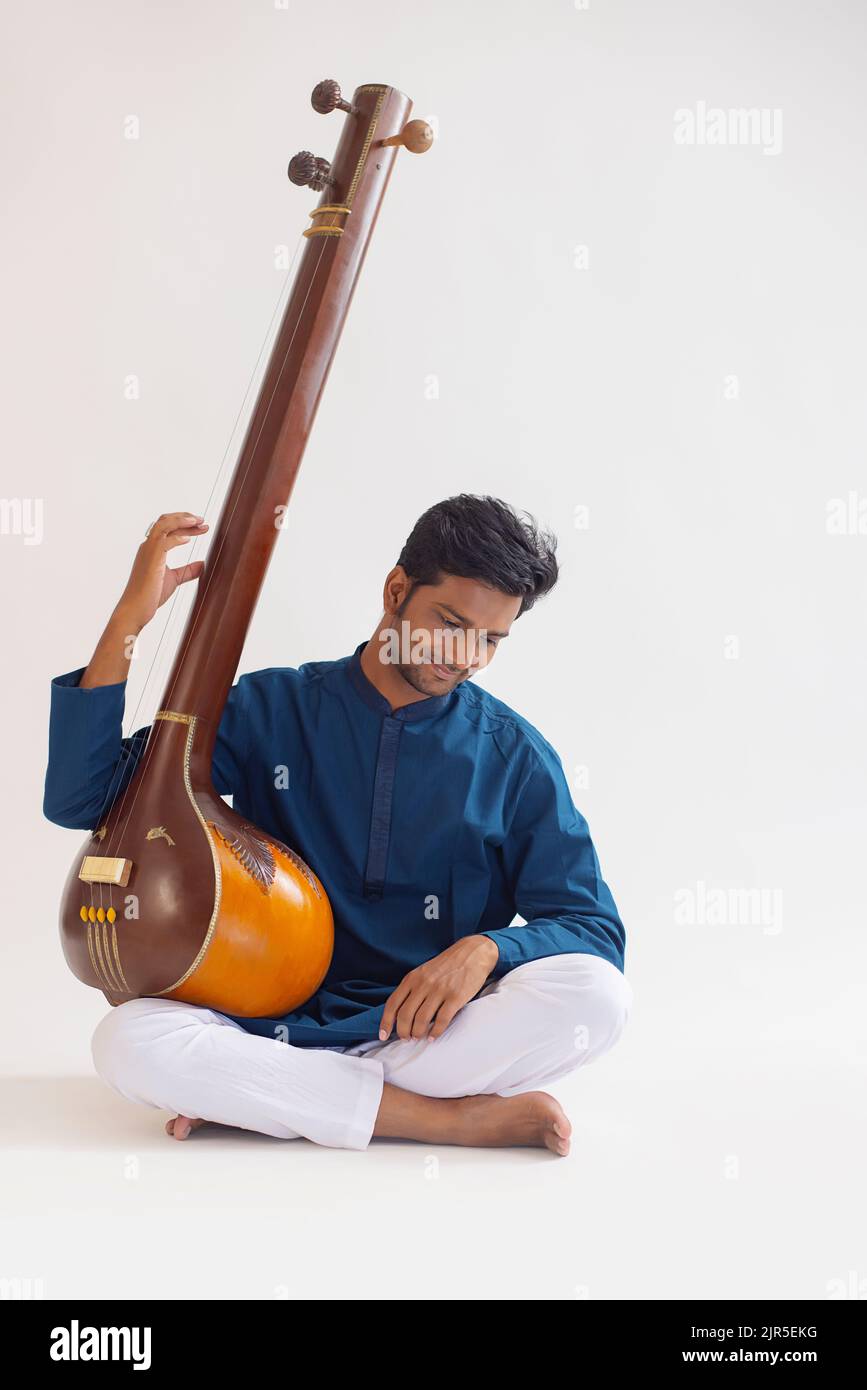 Portrait of young man playing Tanpura against white background Stock ...