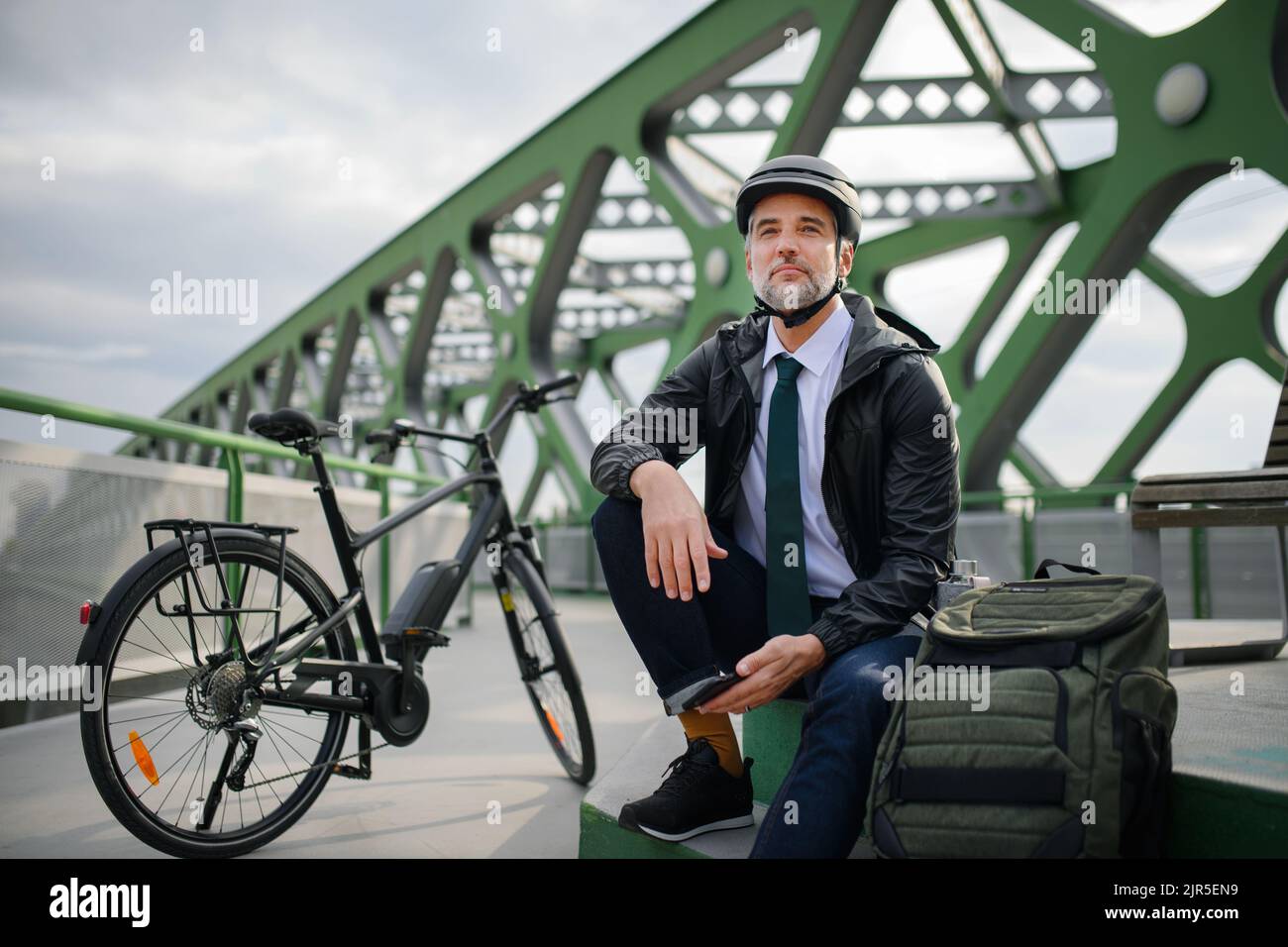 Businessman with bike sitting on bench, using smartphone. Commuting and ...