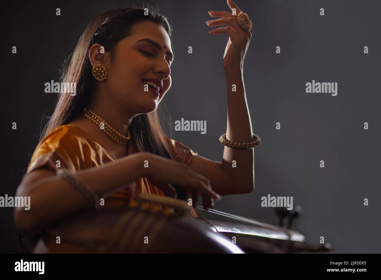 Close-up view of a female musician performing with Tanpura at concert ...