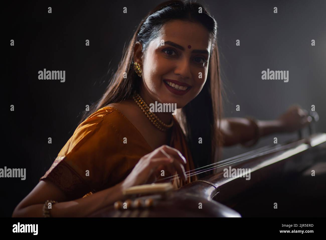 Close-up view of a female musician performing with Tanpura at concert ...