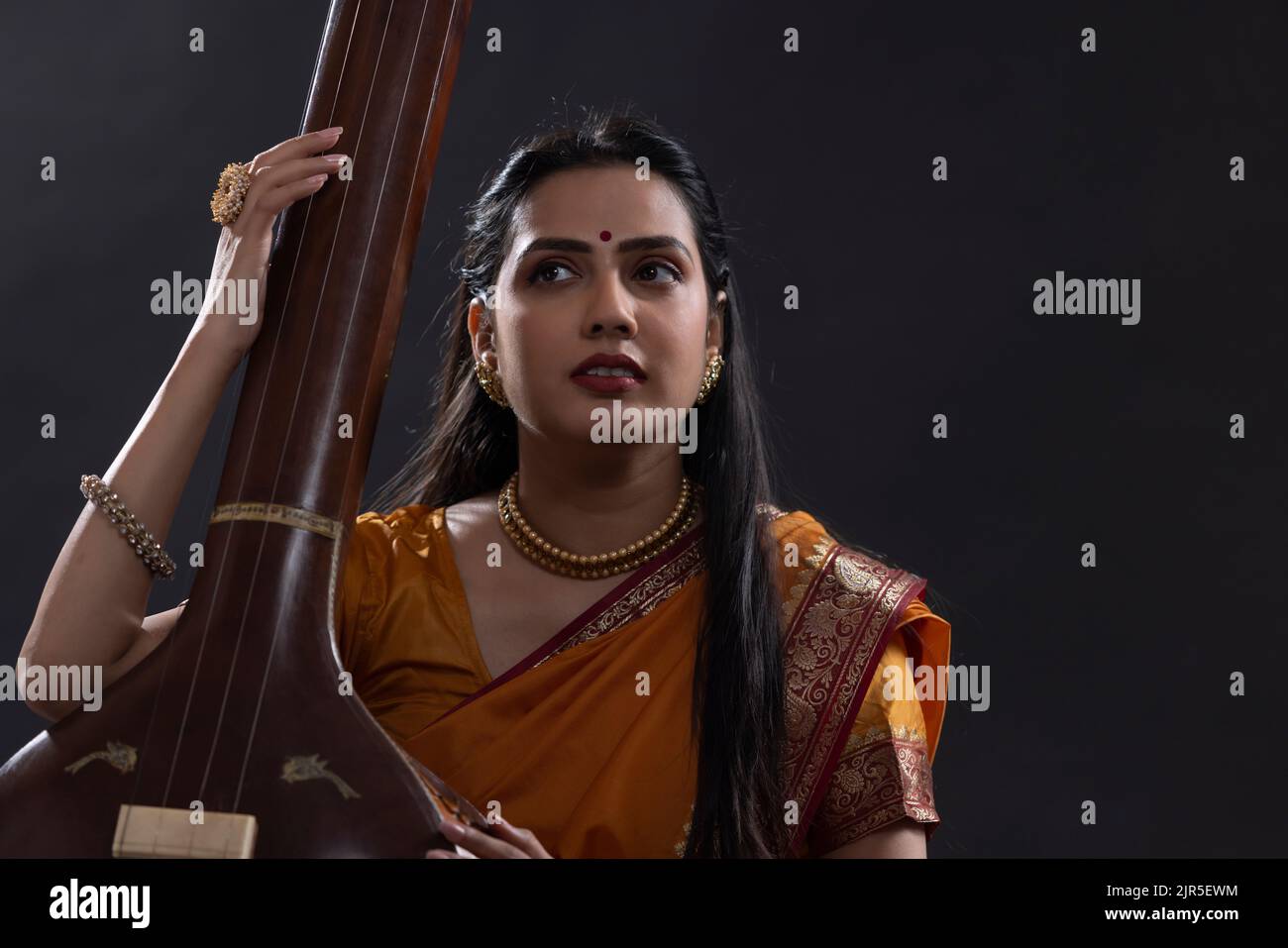 Close-up view of a female musician performing with Tanpura at concert ...