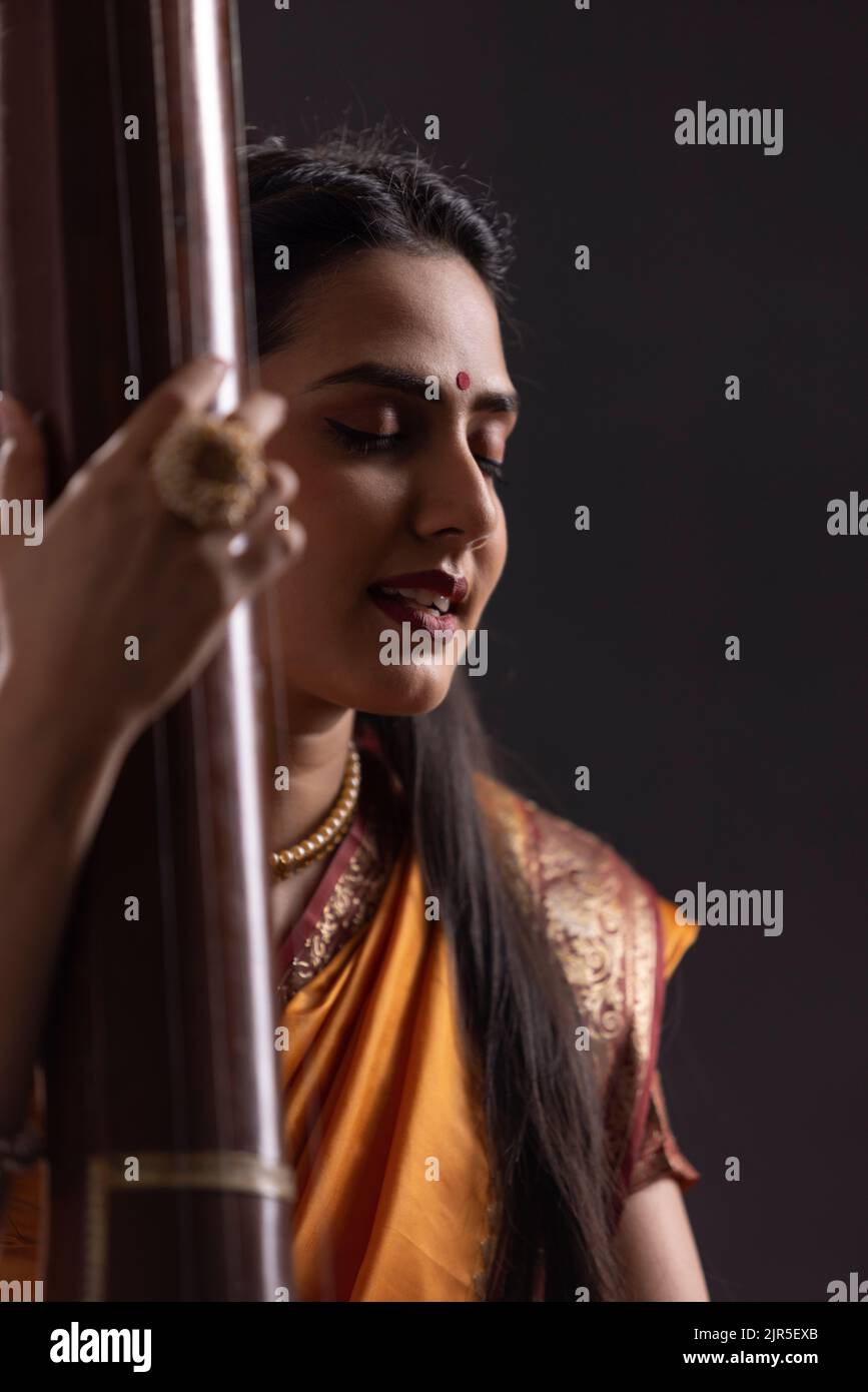 Close-up view of a female musician performing with Tanpura at concert ...