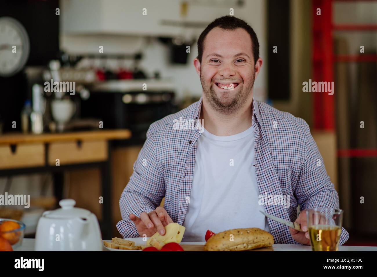 Independent man with down syndrome preparing brekfast in his apartment ...
