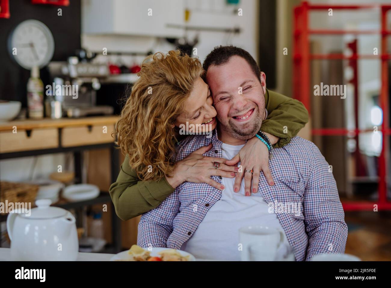 Portrait of mother hugging her grown up son with Down syndrome, motherhood concept. Looking at ...