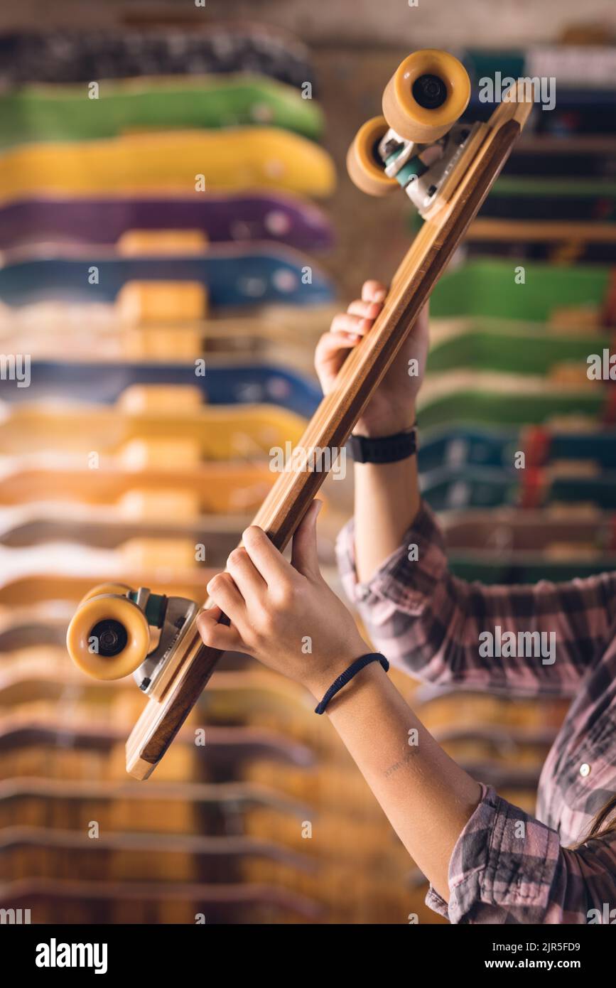 Image of hands of caucasian woman holding skateboard in skate shop ...