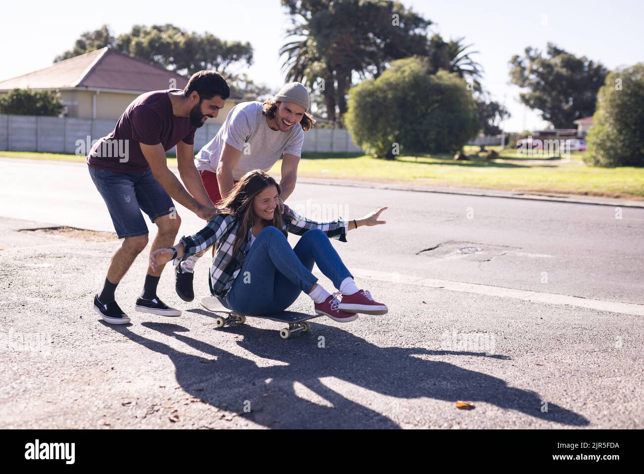 Image of happy diverse female and male friends having fun on skateboard ...
