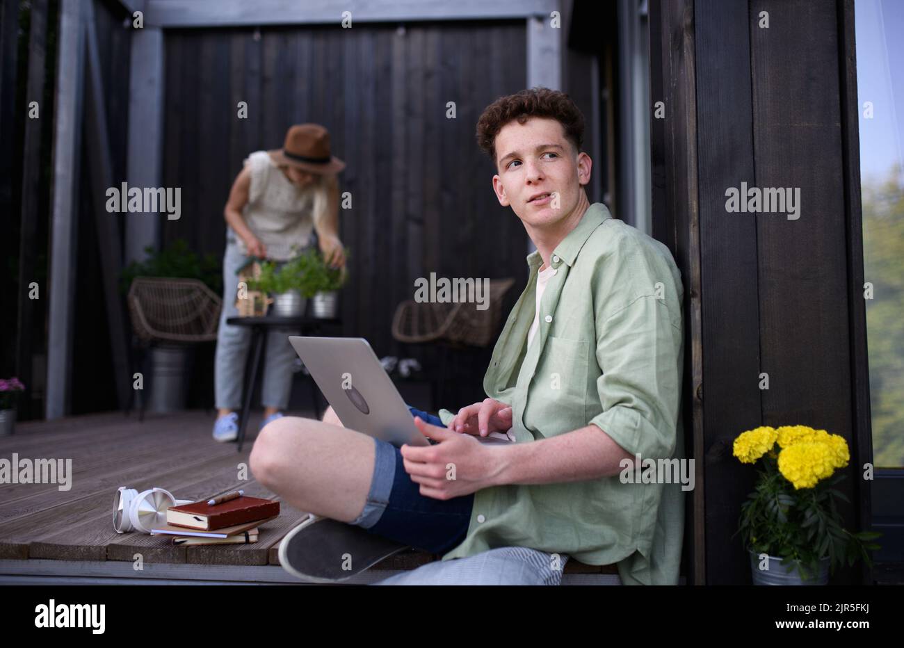 Happy young couple with laptop resting outdoors in a tiny house ...