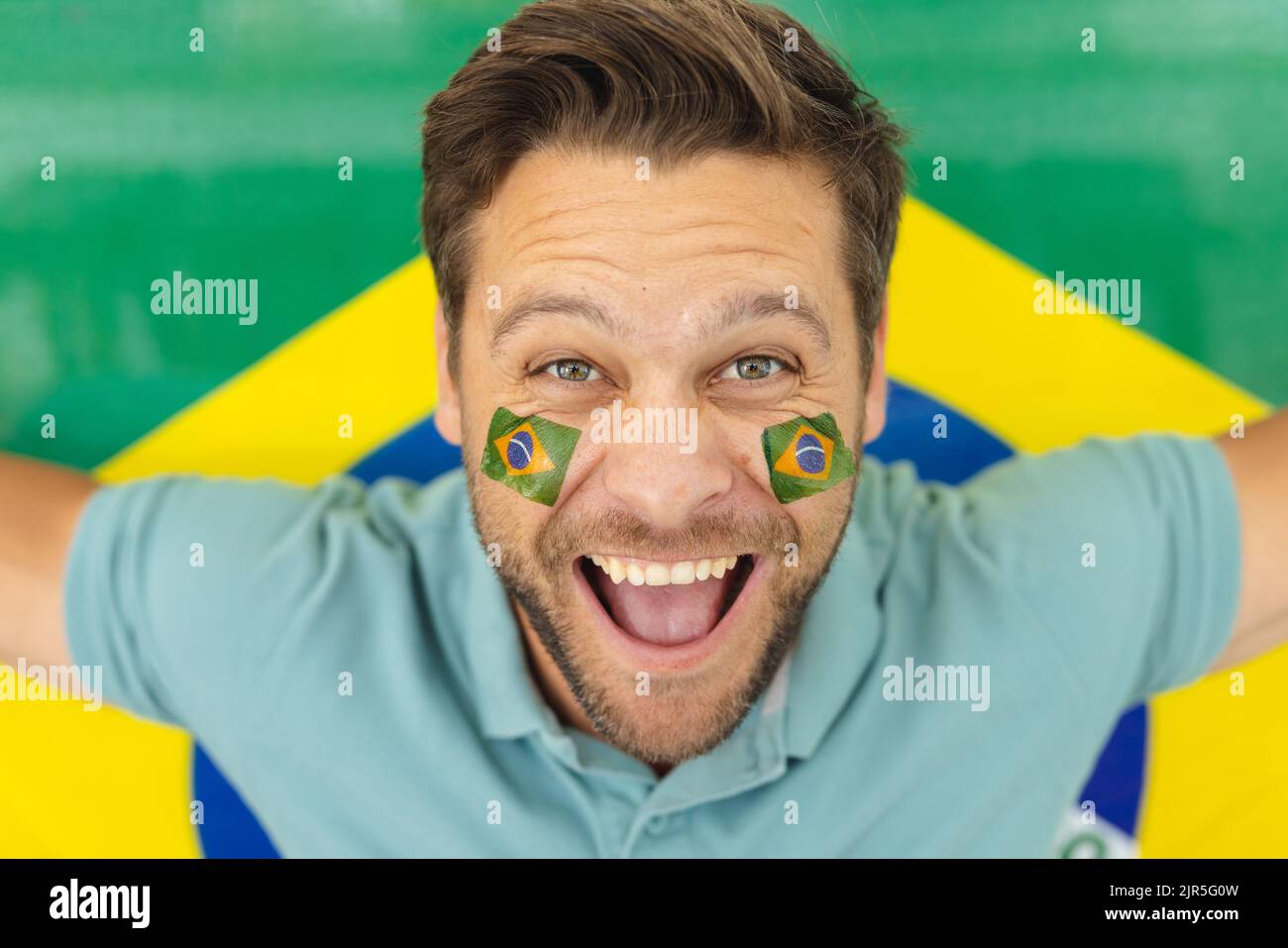 Image of happy caucasian man with flags of brazil on face over flag of ...