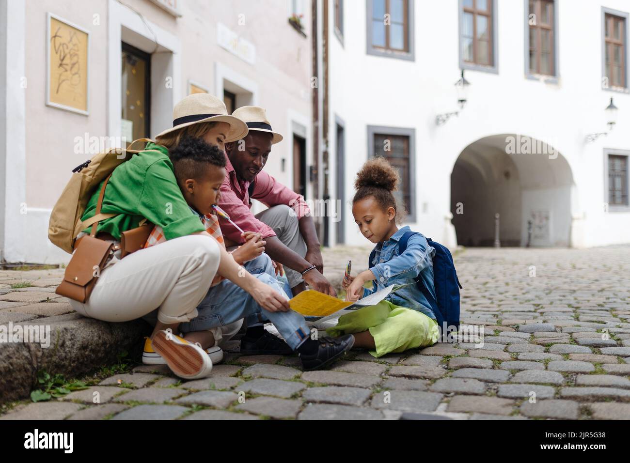 Multiracial family travel together with suitcases, sitting on ground ...