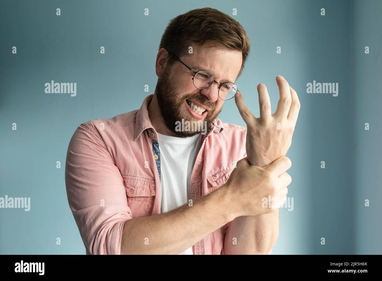 Man with glasses is experiencing severe pain in arm, he is massaging ...