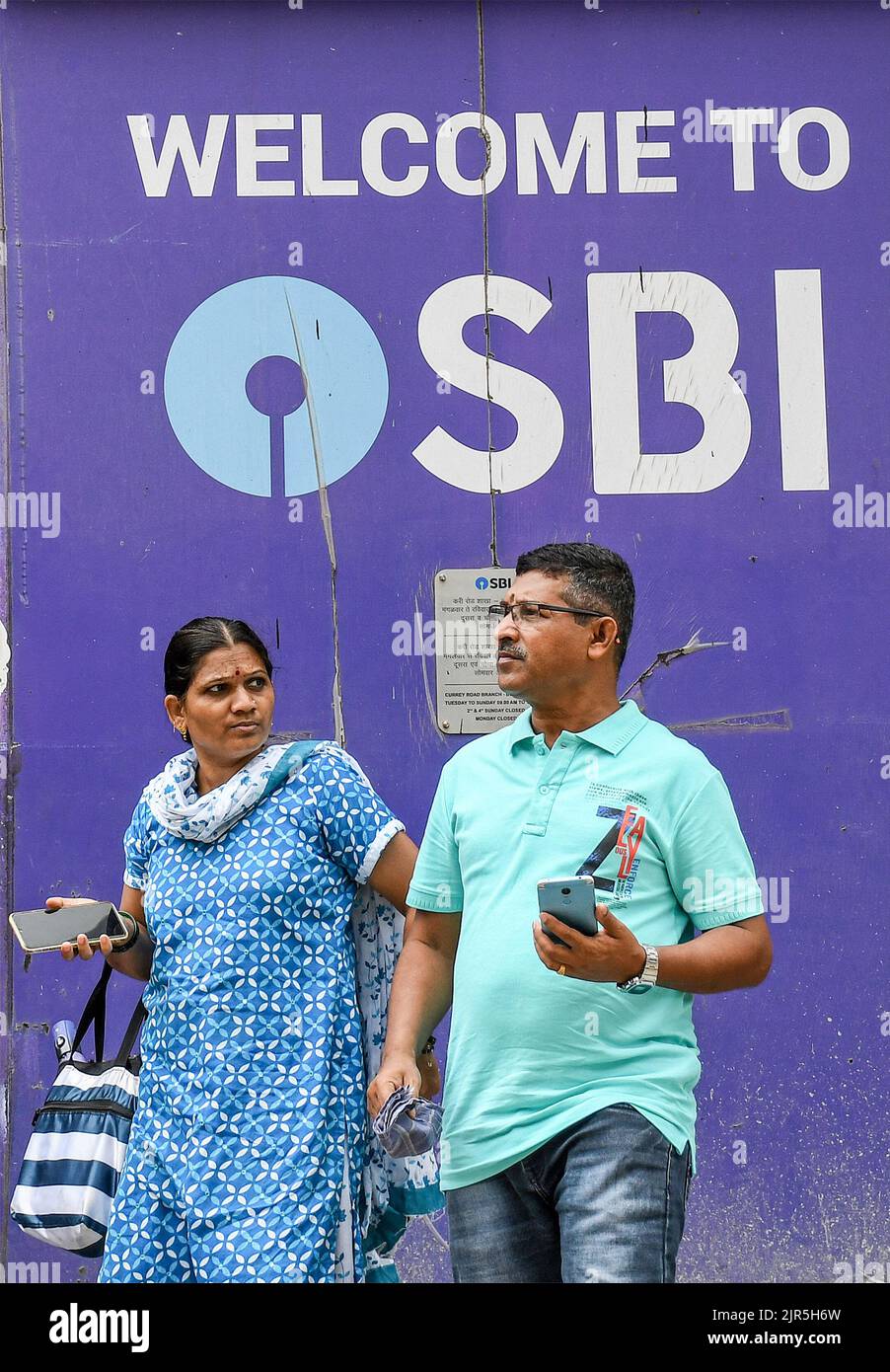 Mumbai, India. 21st Aug, 2022. People walk past a logo of State Bank of ...