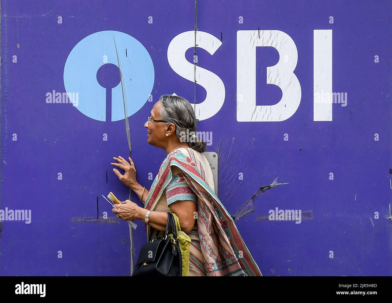 Mumbai, India. 21st Aug, 2022. A woman walks past a logo of State Bank ...