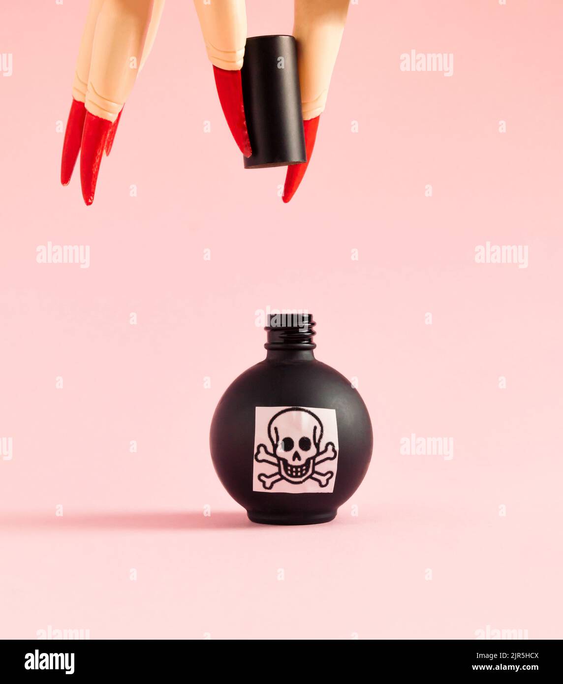 Witch's hand with red nails and poison in black bottle against pastel ...