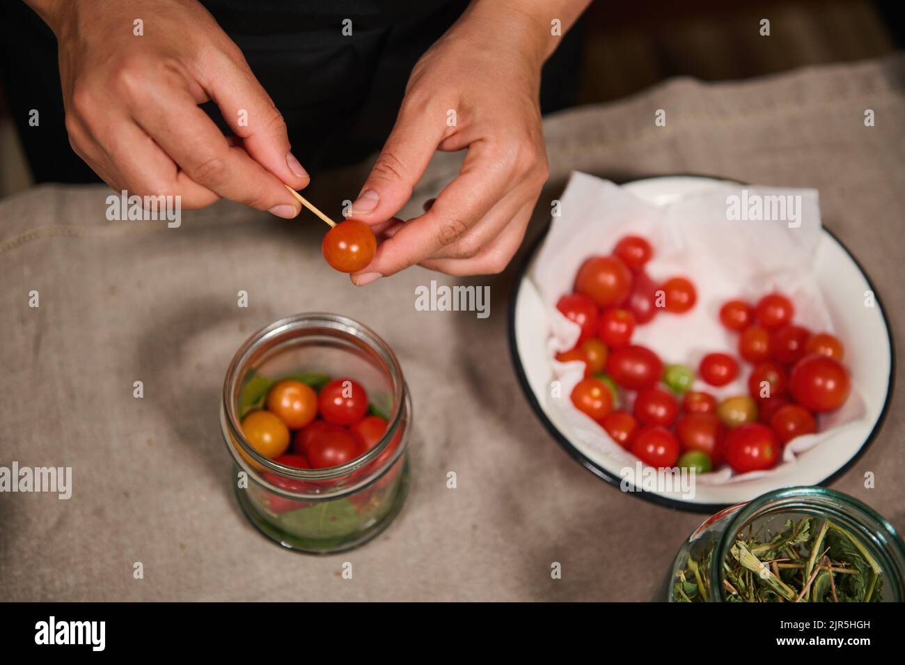 Overhead view of a housewife in black chef's apron pickling ripe and ...