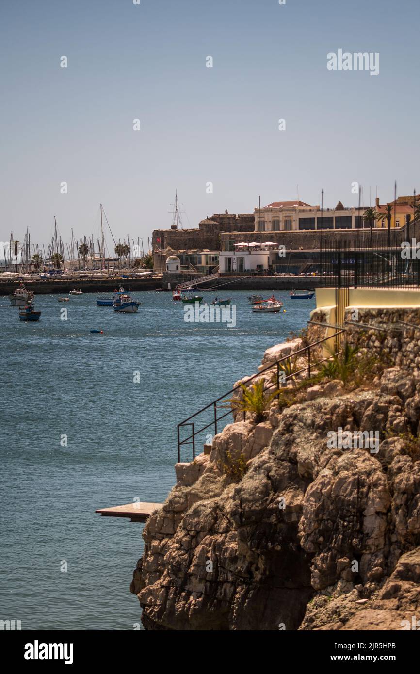 Cliff with railing down to a diving board next to a marina in the sea ...