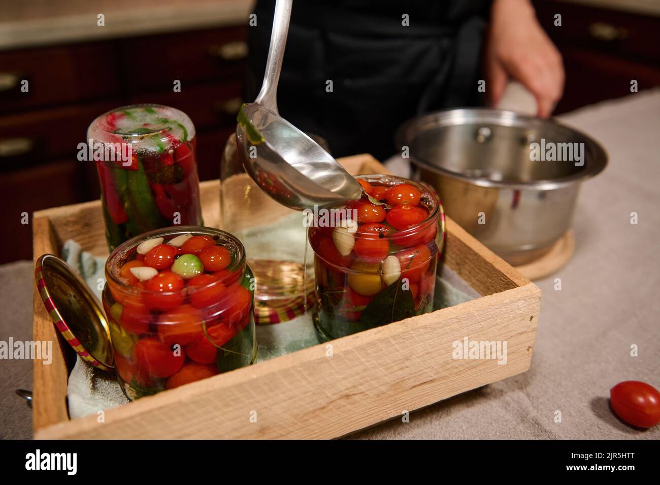 Pouring boiling marinade into jars with cherry tomatoes. Canning ...