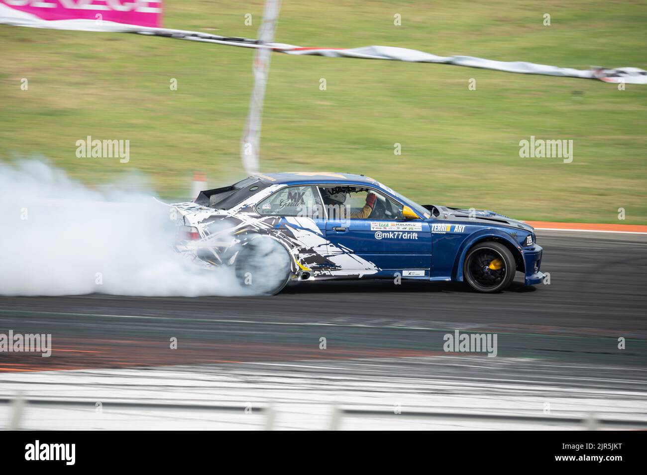 A white and blue BMW E36 producing smoke on a trail for a drift ...