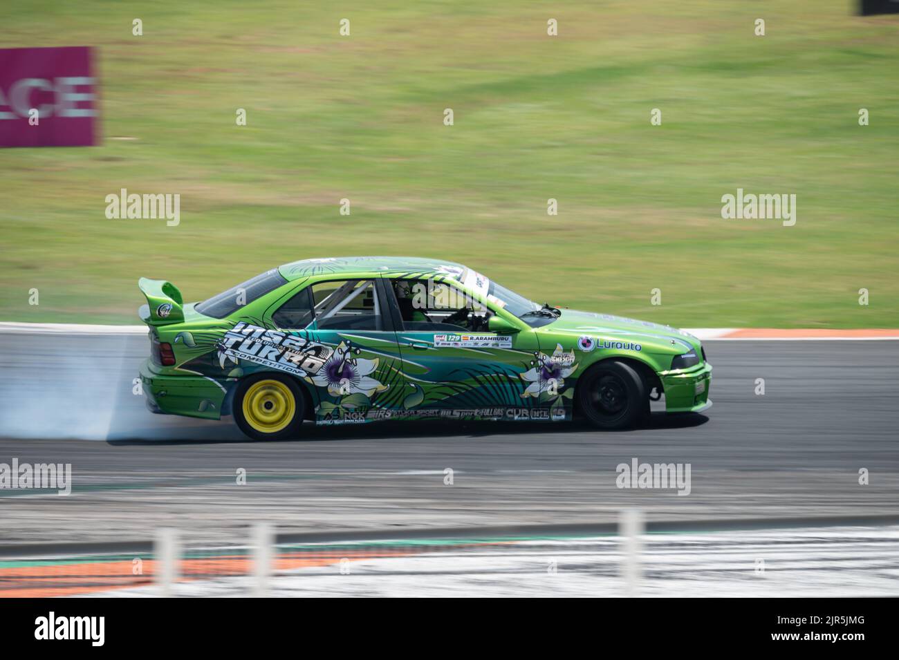 A green BMW E36 producing smoke on a trail for a drift competition ...