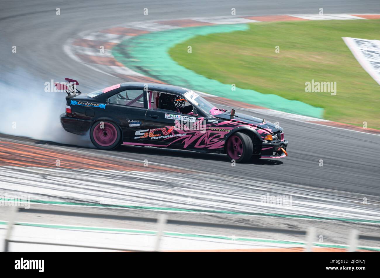 A black pink BMW E36 producing smoke on a trail for a drift competition ...