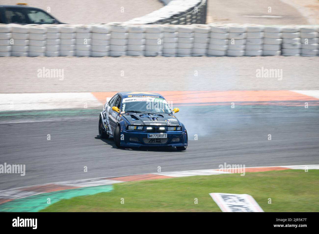 A white and blue BMW E36 producing smoke on a trail for a drift ...