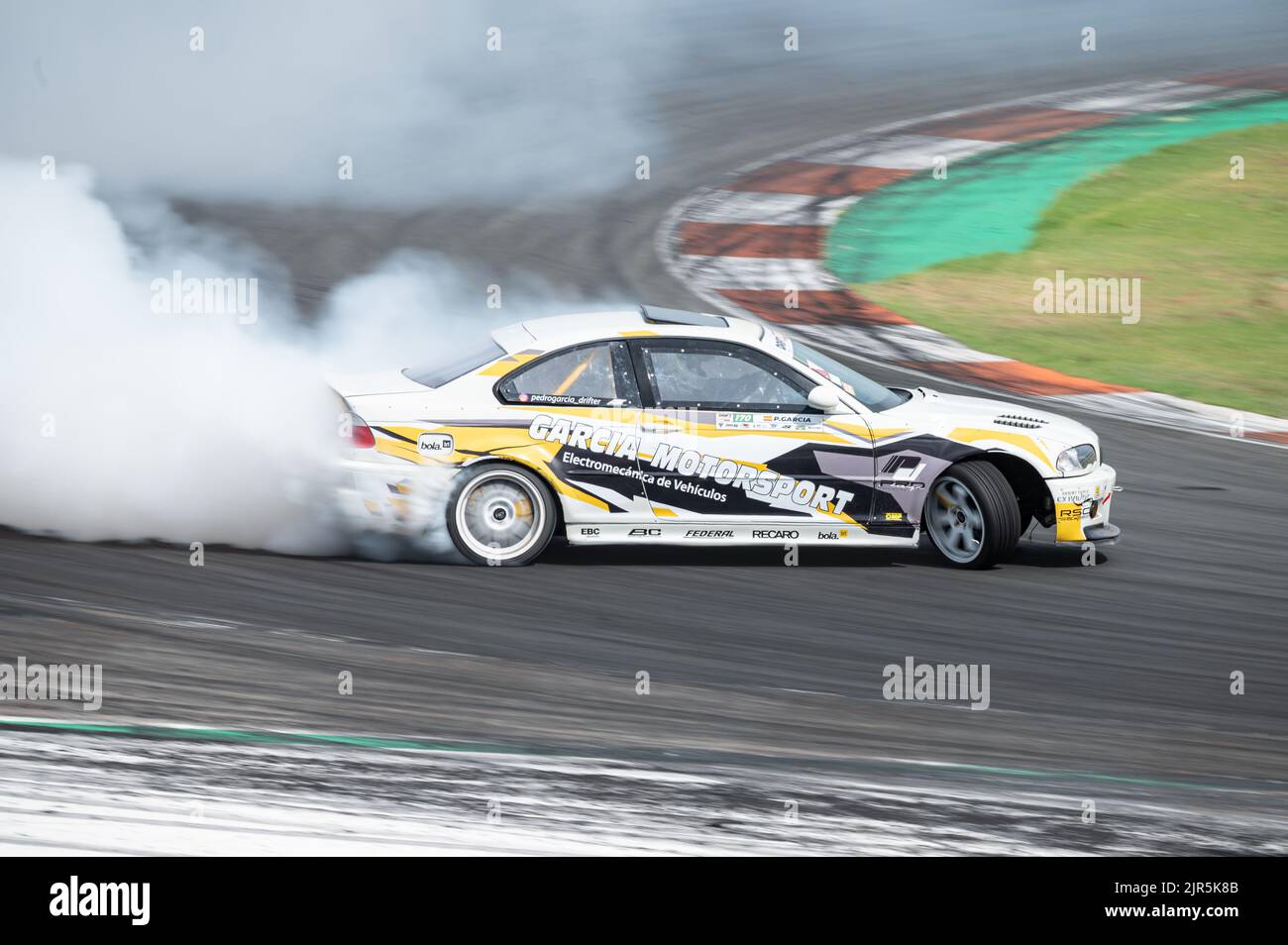 A white black yellow BMW E46 producing smoke on a trail for a drift ...