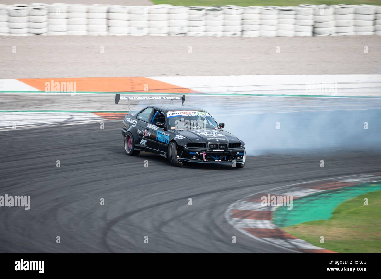 A black BMW E36 producing smoke on a trail for a drift competition ...