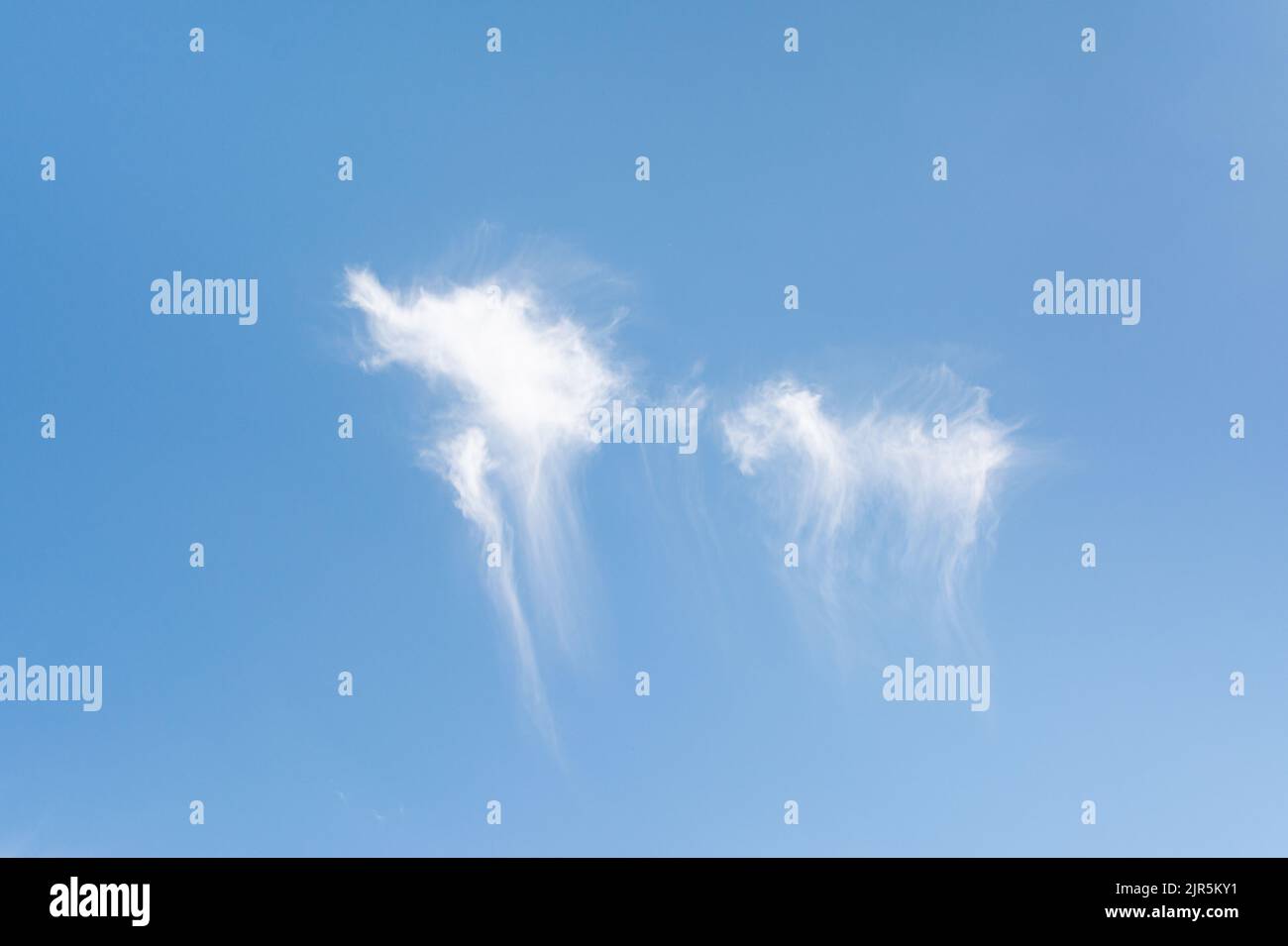 Blue sky with two small clouds and filament trails Stock Photo - Alamy